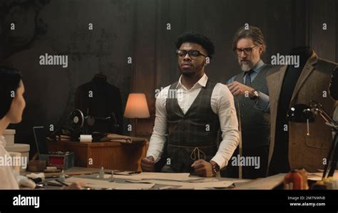 Male Tailor Measures African American Client Discusses With Female Seamstress Design Of