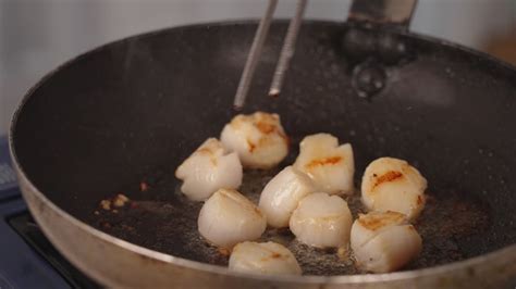 Scallops Cooking And Sizzling On Frying Pan With Oil Popping And Splattering Chef Flipping