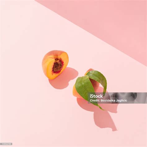 구덩이와 나뭇잎과 햇빛 그림자가있는 절단 복숭아 조각으로 만든 트렌디 한 신선한 과일 구성 최소한의 파스텔 복숭아 핑크 배경 창조적 인 건강 식품 개념 낭만적 인 여름 파티