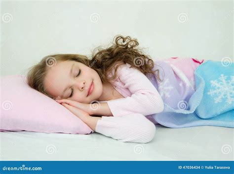 Прелестная маленькая девочка спать в ее кровати Стоковое Фото изображение насчитывающей