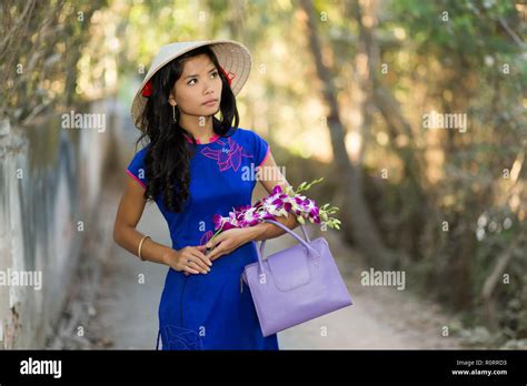 Hübsche junge Vietnamesin in einem eleganten blauen Outfit Blumen tragen als sie Spaziergänge