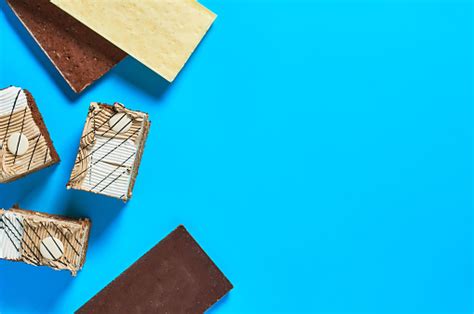 다른 초콜릿 바 옆에 케이크의 세 직사각형 조각은 파티의 파란색 테이블에 놓여있다 축 하 개념입니다 텍스트의 공백입니다 맨 위 보기 3가지 개체에 대한 스톡 사진 및 기타