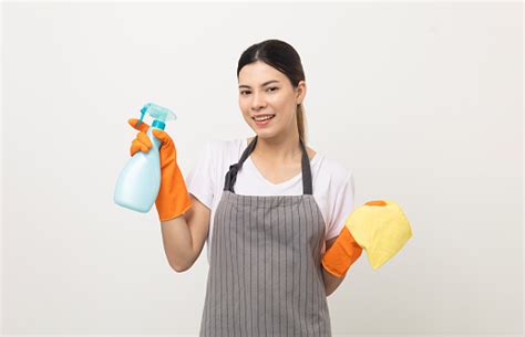 앞치마와 고무 장갑을 착용 한 젊은 아름다운 여성은 고립 된 흰색 배경에서 집을 청소할 준비가되었습니다 가사 청소 또는 스프레이