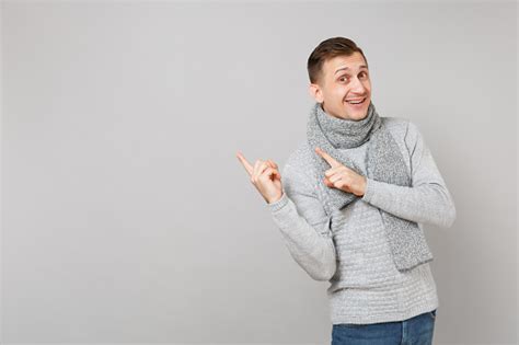 회색 스웨터 스카프 가리키는 인덱스 손가락 옆으로 스튜디오에 회색 배경에 고립에서 젊은 남자를 놀 랐 다 건강 패션 라이프
