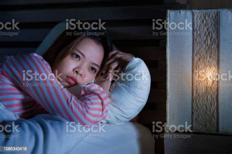 Young Beautiful Sad And Depressed Asian Chinese Girl Lying On Bed Late ...