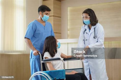 외과 용 얼굴 마스크를 착용하고 병원에서 휠체어에 환자와 위로하는 다양한 의사 팀의 그룹 코로나바이러스 전염병 또는