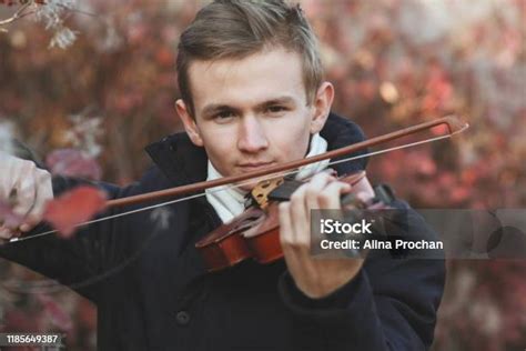 가을 자연에 바이올린을 연주 하는 젊은 우아한 남자의 얼굴 Backgroung 자신 있게 똑바로 찾고 악기 연습 야외 공연 취미와 예술의 개념소년 Classical
