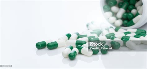 녹색과 흰색 캡슐 알약이 알약 병에서 퍼집니다 건강 관리 및 의학 처방약 제약 산업 암 표적 치료 및 면역 요법 약물 연구 및