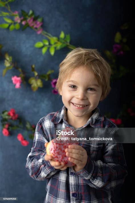귀여운 작은 금발의 아이 유치원 소년 발렌타인 데이를 위해 만든 마음의 모양에 분홍색 도넛을 먹고 건강에 좋지 않은 음식에 대한