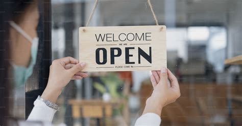 재개장 젊은 아시아 소녀는 폐쇄 후 표지판을 닫힌 표지판에서 열린 표지판으로 바꾸는 안면 마스크를 착용합니다 사진