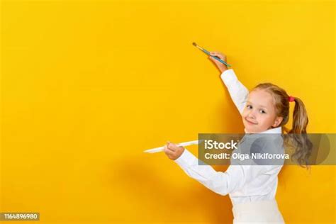 팔레트와 브러시를 들고 어린 소녀 한 어린이가 노란 빈 벽에 그림을 그리고 있다 그리기에 대한 스톡 사진 및 기타 이미지