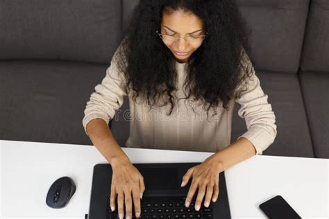 cheerful black woman working on laptop computer at home overhead photo