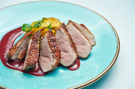 회색 배경에 고립 된 파란색 접시에 베리 소스와 사과를 곁들인 구운 오리 필레를 식욕을 돋우고 있습니다 닫아 0명에 대한 스톡 사진 및 기타 이미지 Istock