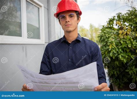 An Engineer With A Floor Plan In Hand Wears A Protective Case On The