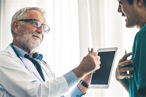 병원에서 다른 의사와 토론 하는 동안 태블릿 컴퓨터를 사용 하 여 수석 남성 의사 의료 의료 직원과 의사 서비스 의사에 대한 스톡 사진 및 기타 이미지 Istock
