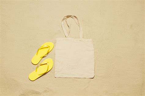 모형 쇼핑객 핸드백 해변 모래 배경 탑 뷰 복사 공간 쇼핑 에코 재사용 가능한 가방 플립 플롭 액세서리 템플릿 빈 평면도 흰색 면 소재 캔버스 천입니다 빈 모형 해변