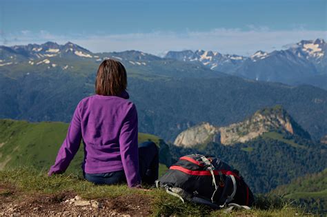 산이 있는 언덕 꼭대기에 배낭을 메고 있는 여자 산이 내려다보이는 풀밭에 앉아 있는 여자 20 24세에 대한 스톡 사진 및 기타 이미지 20 24세 건강한 생활방식