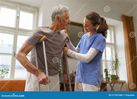 Enfermera Joven Ayudando A Un Anciano Caminando Imagen De Archivo