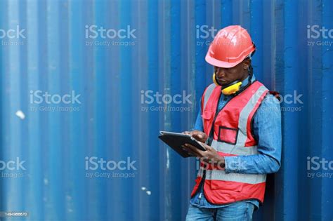 태블릿과 워키토키 무선 조종 적재 컨테이너 상자를 사용하는 감독 안전모를 쓴 엔지니어 또는 작업자는 컨테이너 화물 현장에서 작업하고 산업용 컨테이너 화물 화물선을 점검합니다