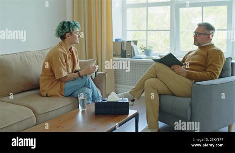 Girl With Prosthetic Arm Having Therapy Session With Psychologist Stock