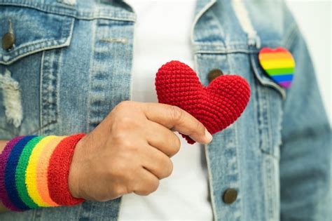 무지개 깃발 팔찌를 착용하고 Lgbt 프라이드의 달의 붉은 심장 상징을 들고 있는 아시아 여성은 게이 레즈비언 양성애자 트랜스