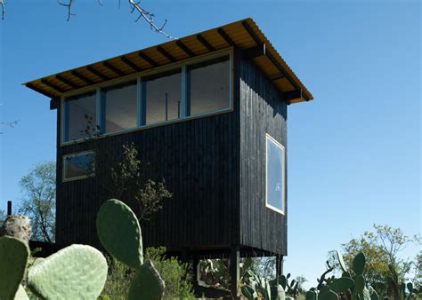 Charred Cabin By Draa Is A Blackened Timber Shelter On Stilts