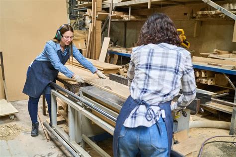 Young Women Collaborating In A Busy Lumberyard Workshop Stock Image Image Of Gloves Young