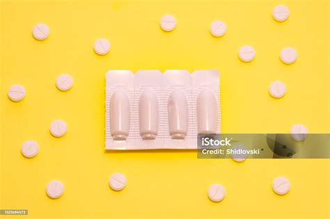 오줌 구의 질병의 좌약의 형태로 제약을 가진 처리 약초의 포장은 노란색 배경에 비뇨기과의 색상 흰색 알약으로 둘러싸여 관장에