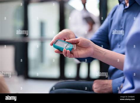 Close Up Of Medical Assistant Taking Old Patient Insulin Level Test Using Glucometer During