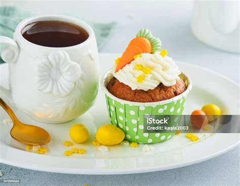 부활절을위한 당근 케이크 컵 케이크 흰색 바탕에 작은 마지팬 당근으로 장식된 크림 치즈 프로스팅을 곁들인 당근 컵케이크 행복한 부활절과 봄 휴가 개념 집에서 만든 성일 가정