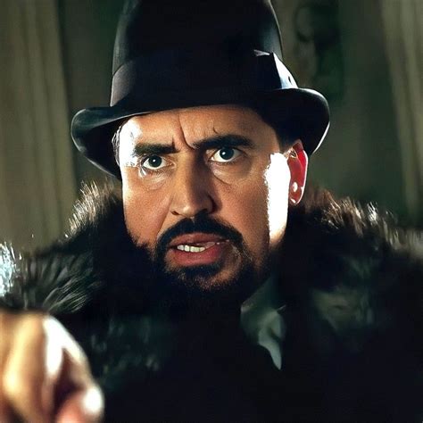 a man wearing a hat and fur coat pointing his finger at the camera with