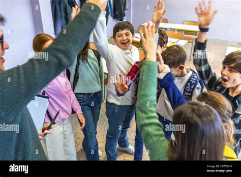 Group Of Cheerful Elementary School Students And Teacher Raising Hands