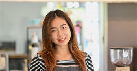 젊은 아시아 여성 바리스타가 커피숍 카운터 앞에 서 있는 빈 태블릿 화면 모형 광고 메뉴 모형을 들고 있다 사진 Unsplash의 태국 이미지