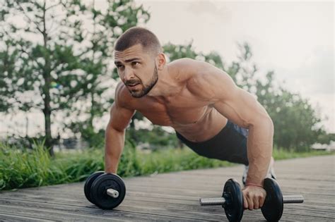 Premium Photo Muscular Male Bodybuilder Does Push Up With Barbells Stands In Plank Pose With