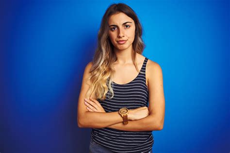 파란색 고립 된 배경 회의적이고 긴장한 위에 줄무늬 티셔츠를 입은 젊은 아름다운 여성은 교차 된 팔로 얼굴에 표정을 거부합니다 부정적인 사람 T 셔츠에 대한 스톡 사진 및