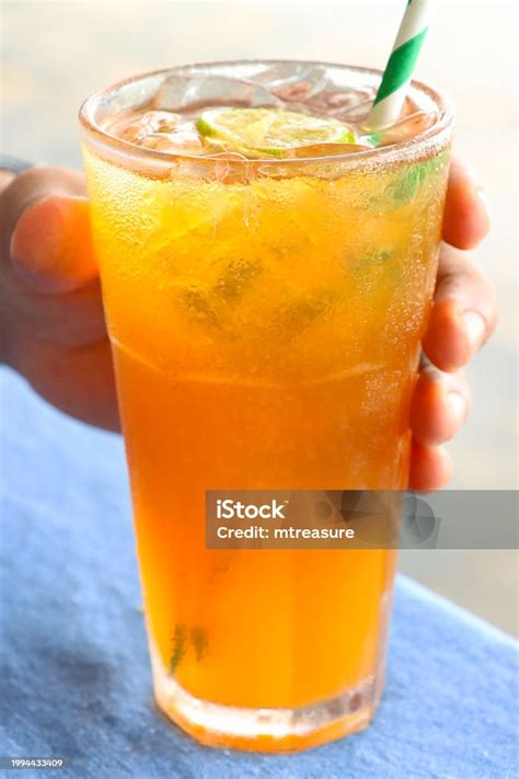 해변 레스토랑 바 장면의 클로즈업 이미지 녹색과 흰색 종이로 감귤류 오렌지 목테일을 들고 있는 알아볼 수 없는 사람 빨대 파란색