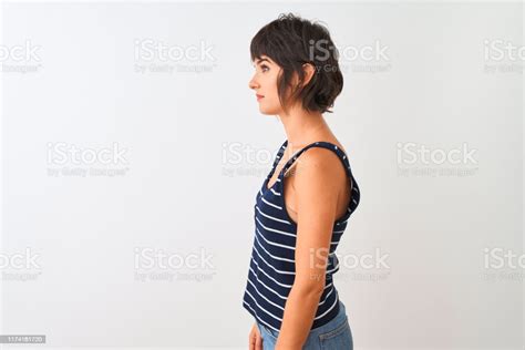 스트라이프 티셔츠를 입은 젊은 여성은 옆으로 보이는 고립 된 흰색 배경 위에 서서 자신감있는 미소로 자연스러운 얼굴로 프로필 포즈를 취합니다 T 셔츠에 대한 스톡 사진 및