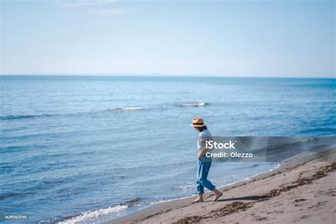 푸른 바다의 모래 해변을 따라 걷는 모자를 쓴 젊은 행복한 여자 여름 방학 및 여행 걷기에 대한 스톡 사진 및 기타 이미지 걷기 관광 관광 리조트 Istock