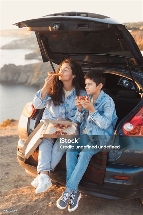 전신 어머니와 십대 아들은 자동차 트렁크에 앉아서 상자에서 피자를 가져 오는 조각을 먹습니다 가족 휴가 여행 차에 대한 스톡 사진 및 기타 이미지 Istock