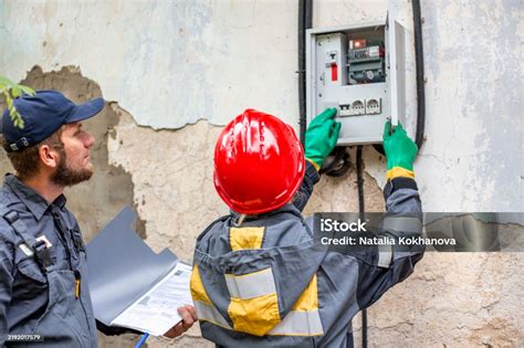 작업자는 전기 계량기의 작동을 확인하고 계량 장치의 판독 값을 확인합니다 전기 소비 모니터링 및 제어 2명에 대한 스톡 사진 및