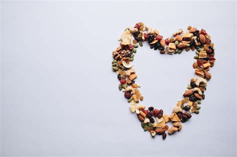 다양한 종류의 건강에 좋은 곡물과 말린 과일이 흰색 배경에 텍스트나 이미지를 위한 빈 공간이 있는 하트 모양으로 배열되어 있습니다 건강한 음식과 체중 감량 건강한 간식