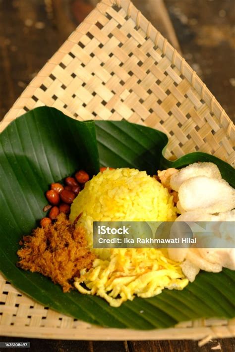 나시 쿠닝은 강황 코코넛 밀크 향신료로 만든 인도네시아의 노란 쌀입니다 쇠고기 치실 크래커 얇게 썬 오믈렛 튀긴 땅콩 바나나 잎에 튀긴 템페와 함께 제공됩니다 길거리 음식