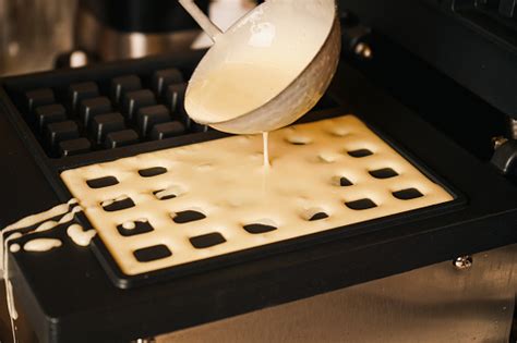 조반 요리 과정 음식 준비 벨기에 와플 만들기 가정의 부엌에 있는 와플 메이커에 반죽을 쏟아 부었습니다 액체 반죽은 벨기에 와플을 준비하기 위해 와플 철 기계를 부었습니다