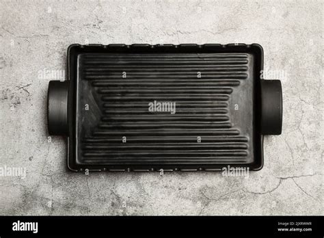 A Rectangular Black Serving Platter With Handles On A Stone Background