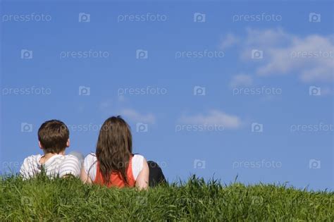 Парень и девушка лежат на траве на фоне голубого неба Stock Image Everypixel