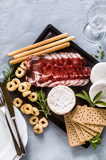 차가운 커트와 치즈는 파란 리넨 축제 식탁보에 향기로운 허브가 있는 화이트 와인 크래커 그리 시 니 및 타 갈리와 테이블의