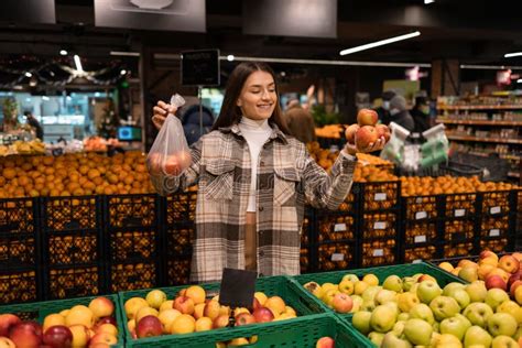 woman in the fruit department of a grocery supermarket buys apples and