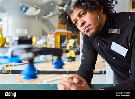 Engineer Attentively Watching A Robotic Gripper Arm In An Industrial