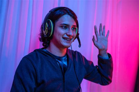 E스포츠 게임이나 스트리머를 하는 잘생긴 소년 온라인 게임을 즐기고 팬을 맞이하고 라이브 쇼 플레이 게임 포커스 모니터 파란색과 빨간색 표시등 20 24세에 대한 스톡 사진