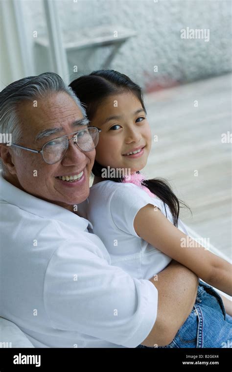 Portrait Of A Girl Sitting On Her Grandfathers Lap And Smiling Stock